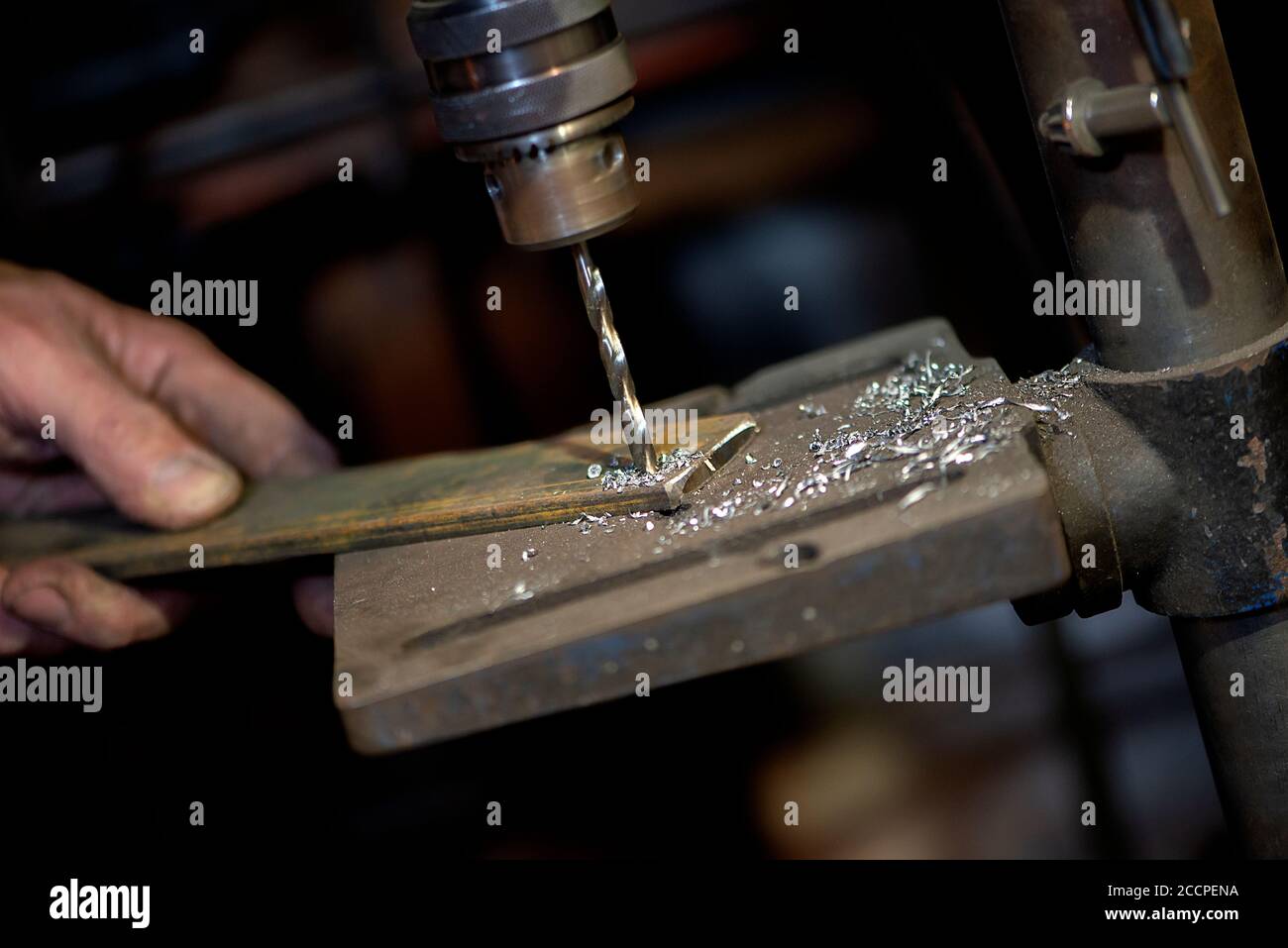 Blacksmith uses drill press in garage. A close up view of a metalworker ...