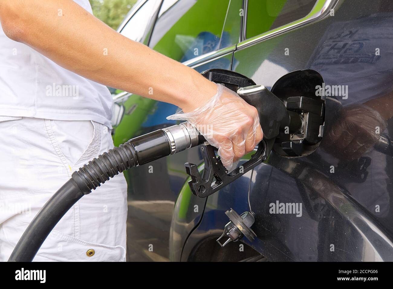a man refueling a black car with diesel fuel at a gas station ...