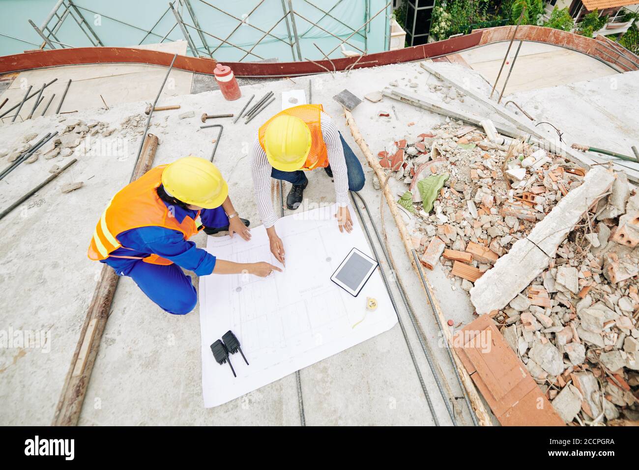 Civil engineers pointing at building plan and discussing details, view ...