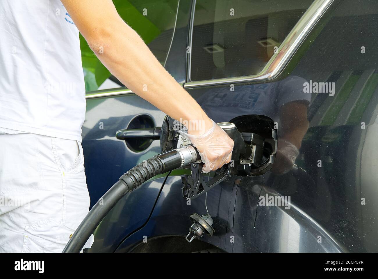 a man refueling a black car with diesel fuel at a gas station ...