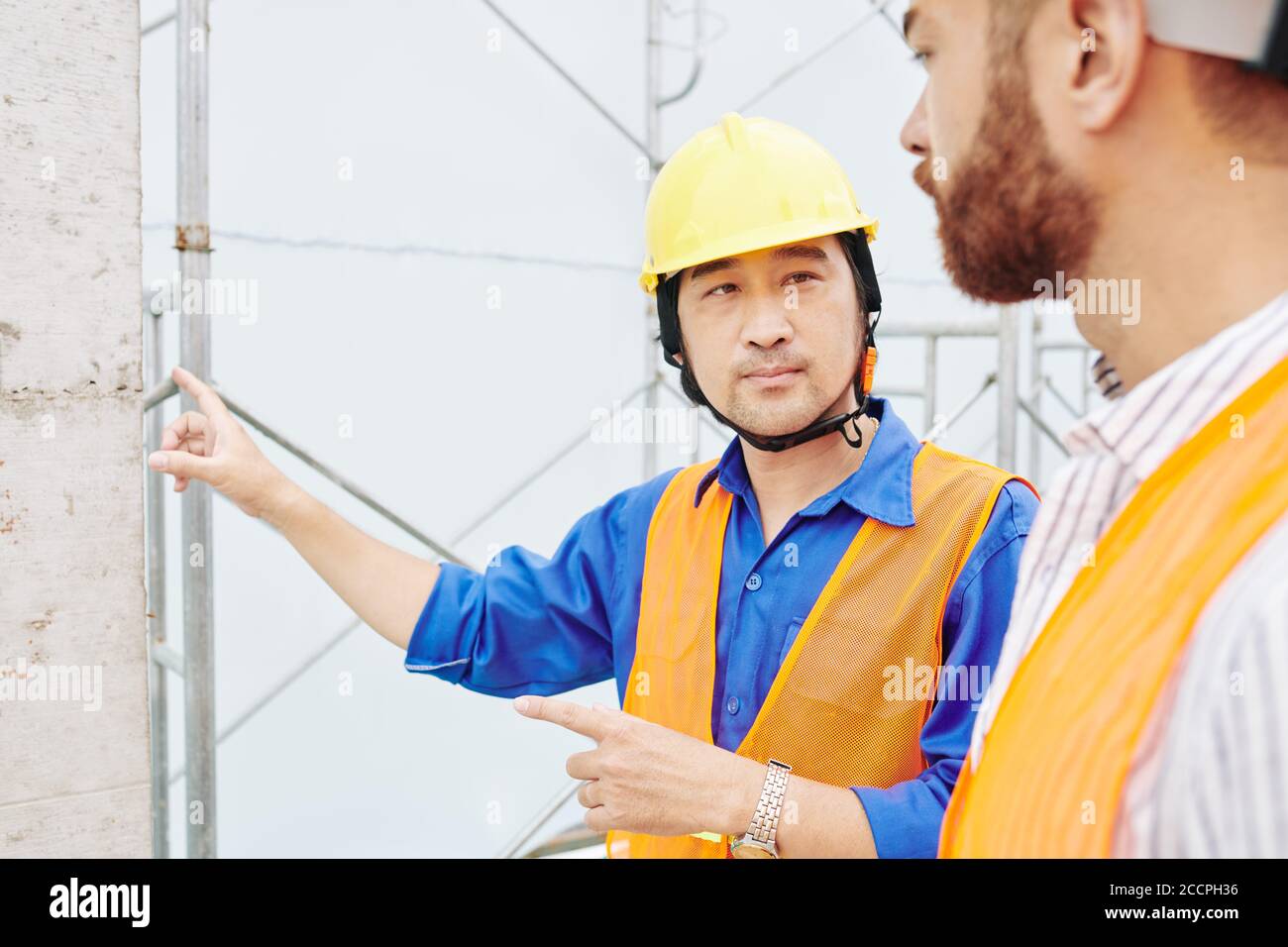 Vietnamese contractor in hardhat showing finished building walls to ...