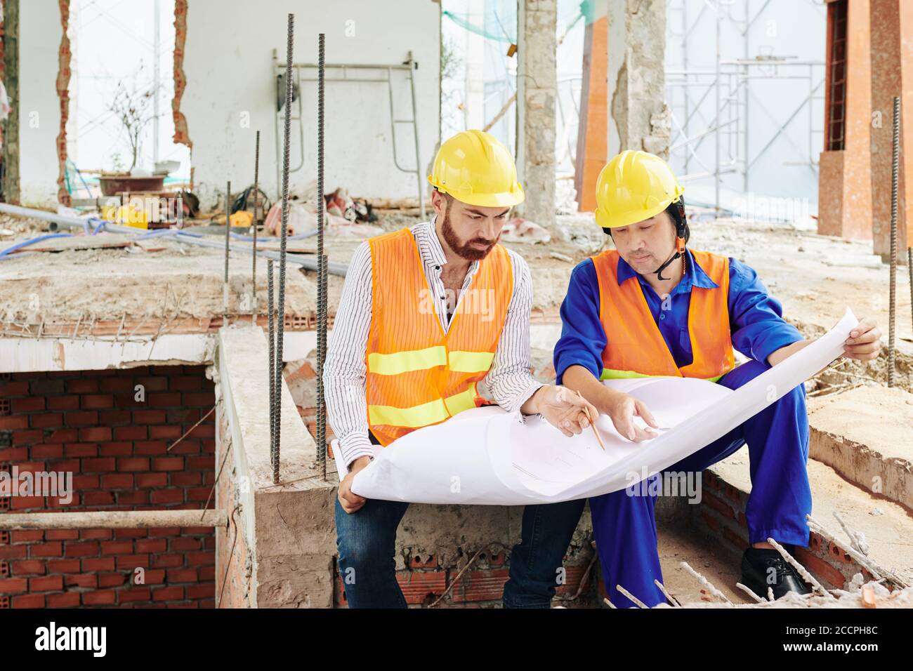 Serious multi-ethnic builders sitting in room of builing under ...