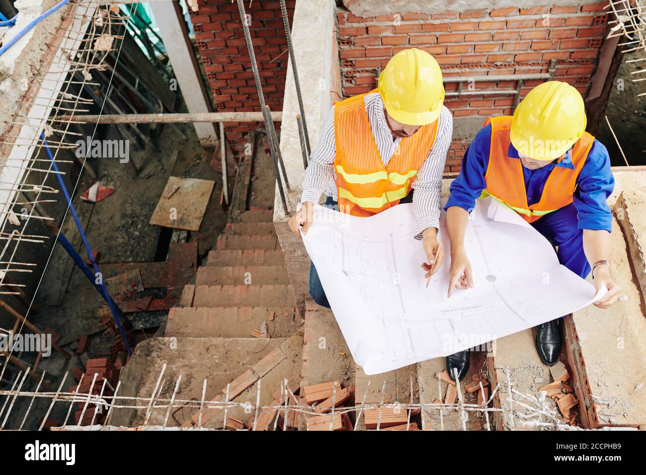 Construction workers sitting on steps inside of building and discussing ...
