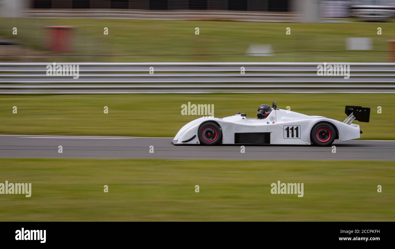 A panning shot of a white racing car as it circuits a track Stock Photo ...