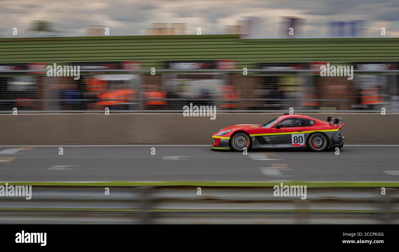 A panning shot of a silver and orange racing car as it circuits a track ...