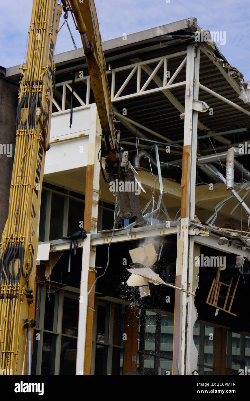 a modern steel structure building being demolished by a machine Stock ...