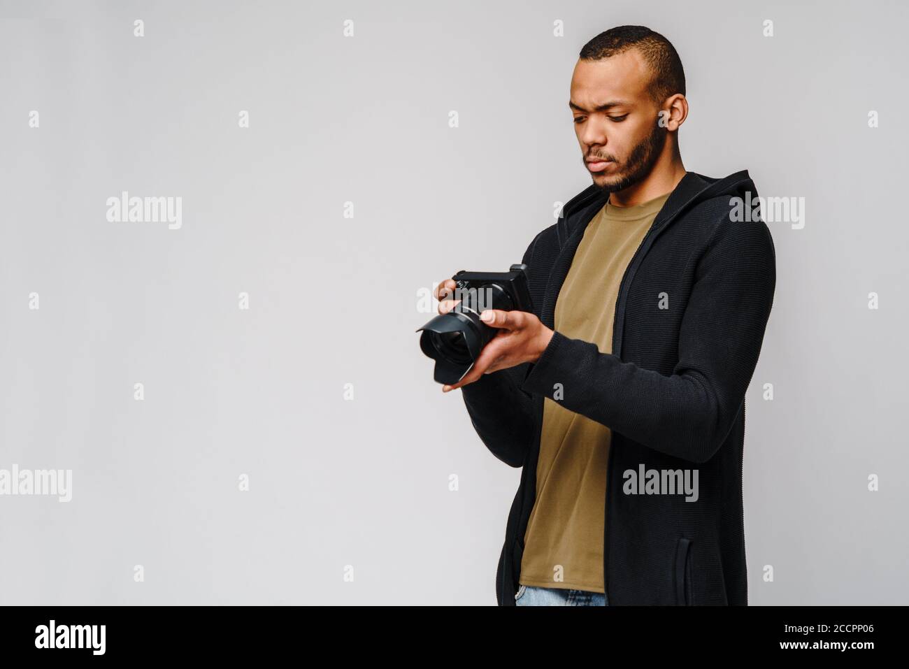 Handsome african american guy holding digital camera over light gray ...