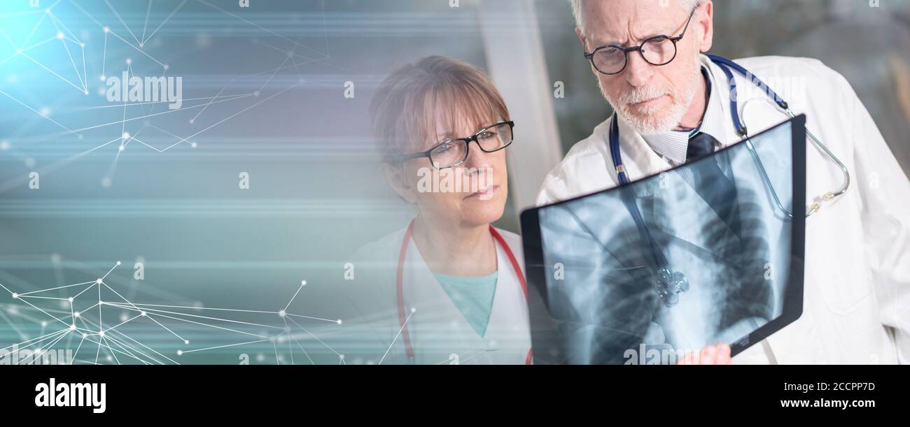 Two doctors examining x-ray report in medical office; panoramic banner ...