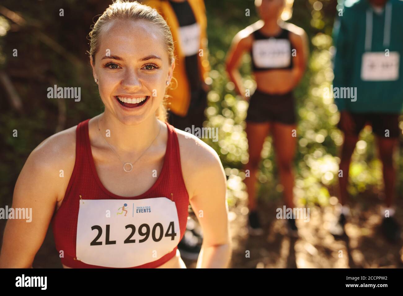 Woman runner standing outdoors looking at camera and smiling. Female in ...