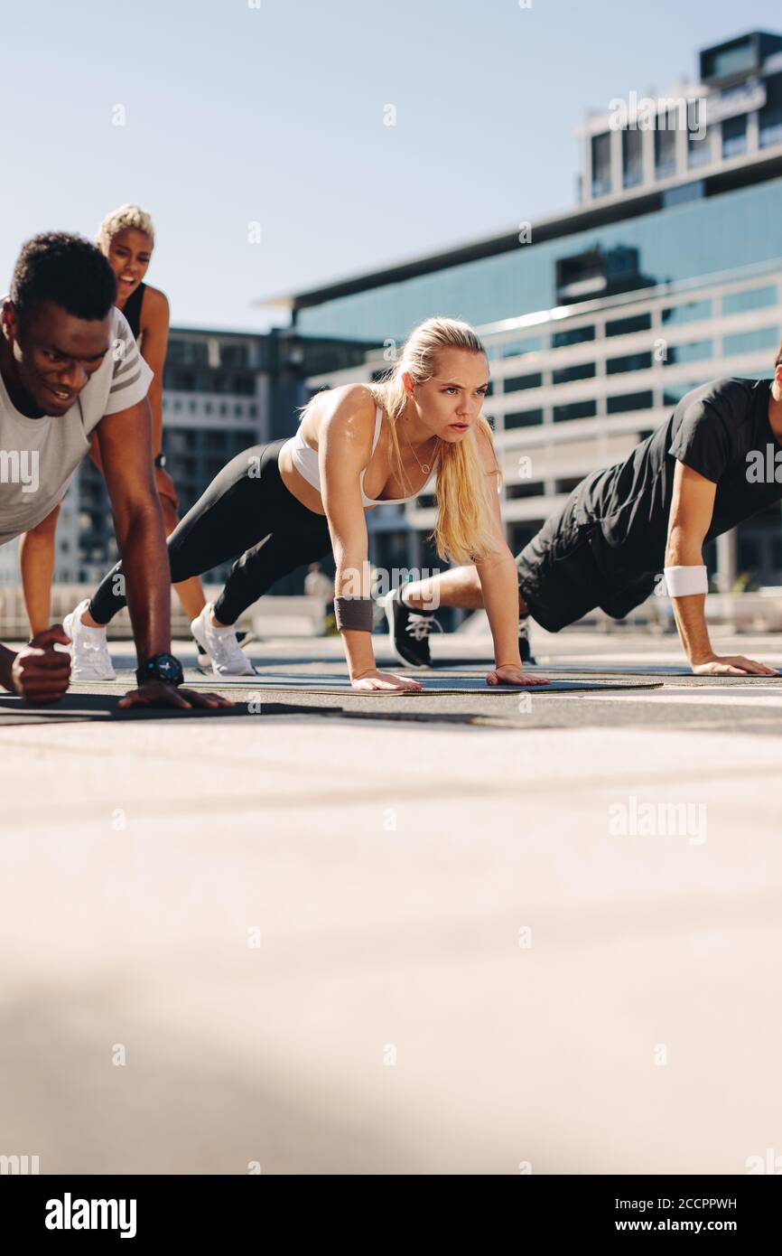 Fit young men and women exercising in the city. Healthy people doing ...