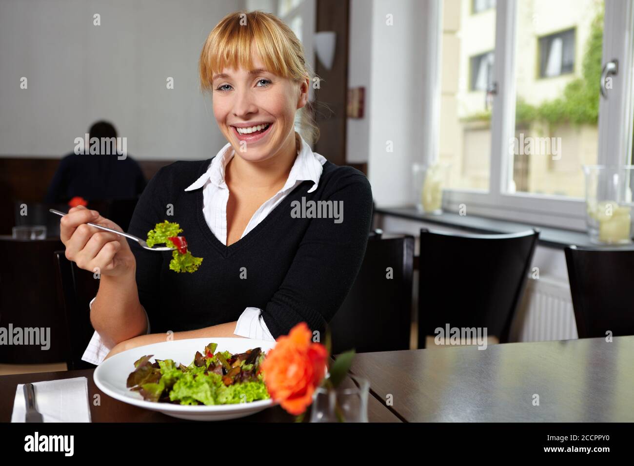 Laughing woman in restaurant with salad on fork Stock Photo - Alamy