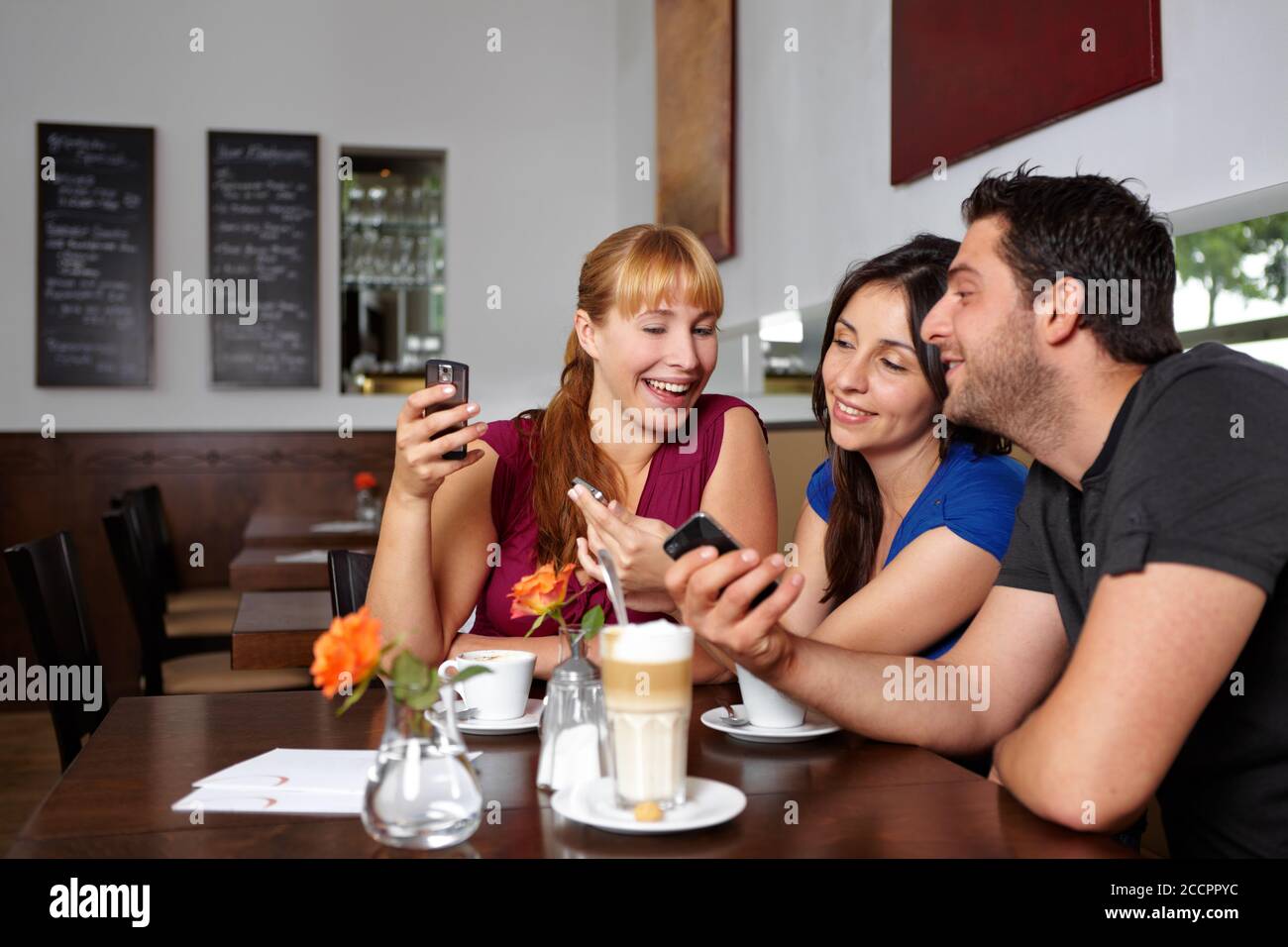 Laughing group plays with their cell phones in the restaurant Stock ...