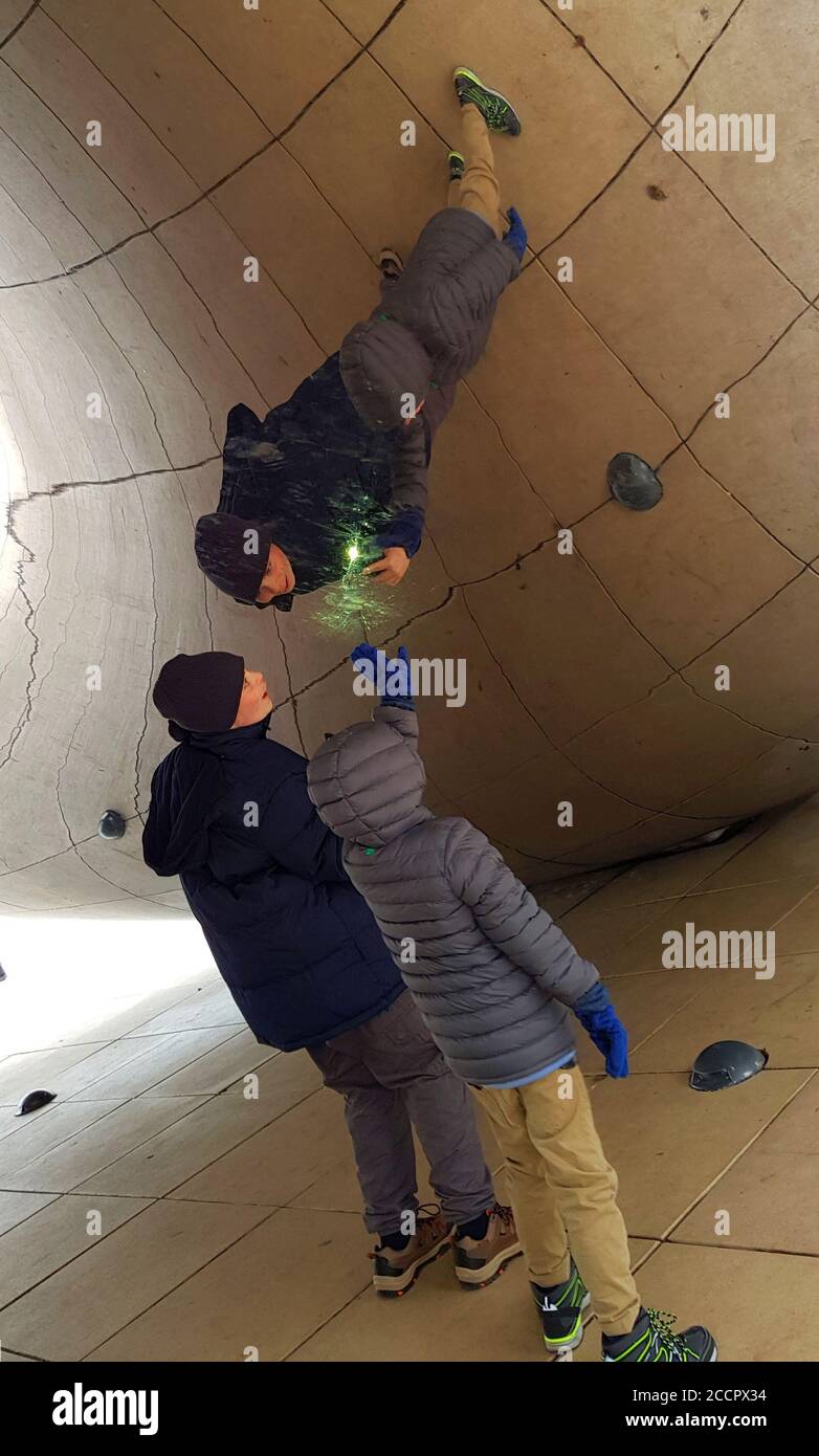 Two young boys look into the reflection of the Cloud Gate sculpture ...