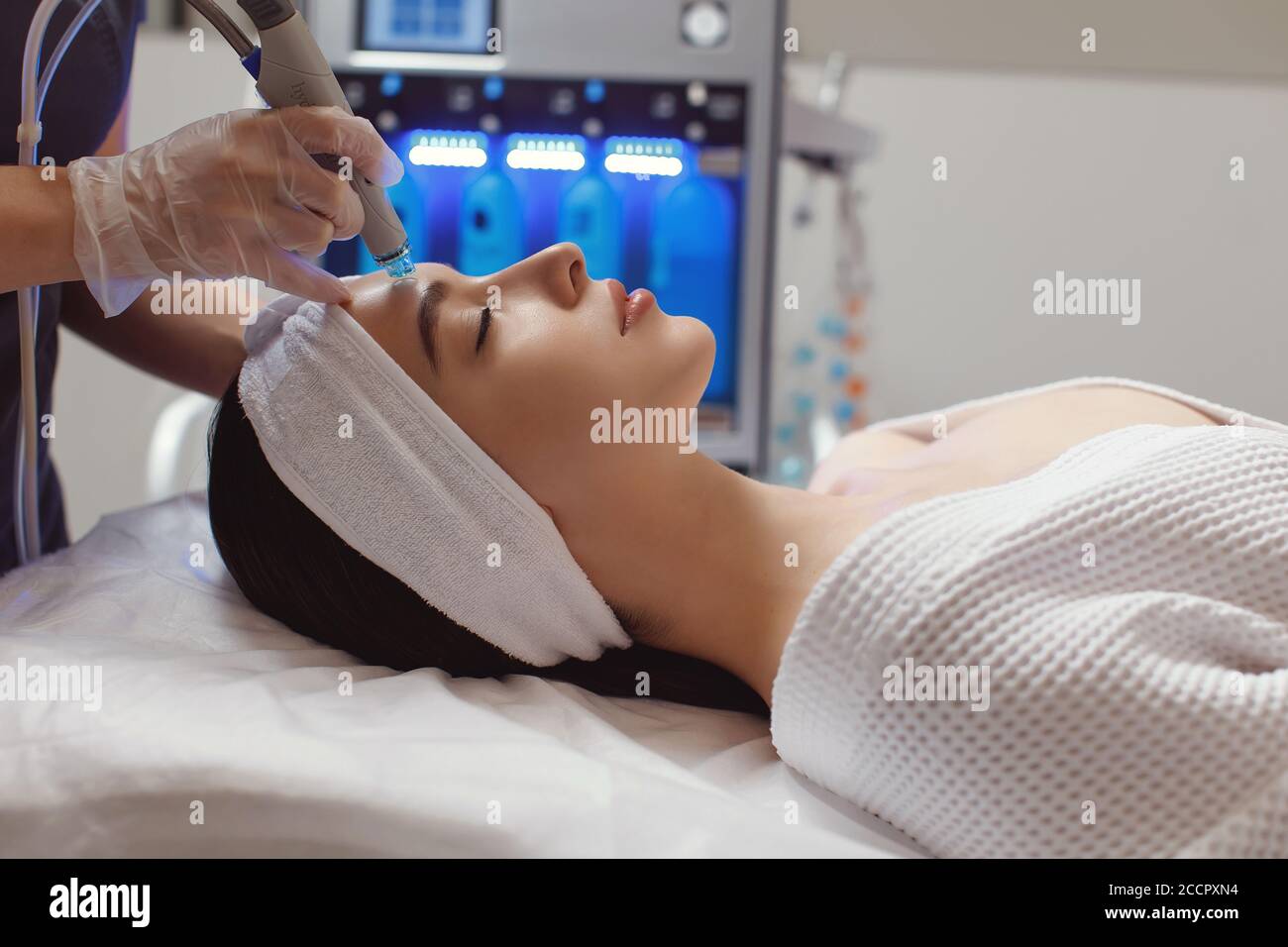 Side view of woman receiving microdermabrasion therapy on forehead at ...