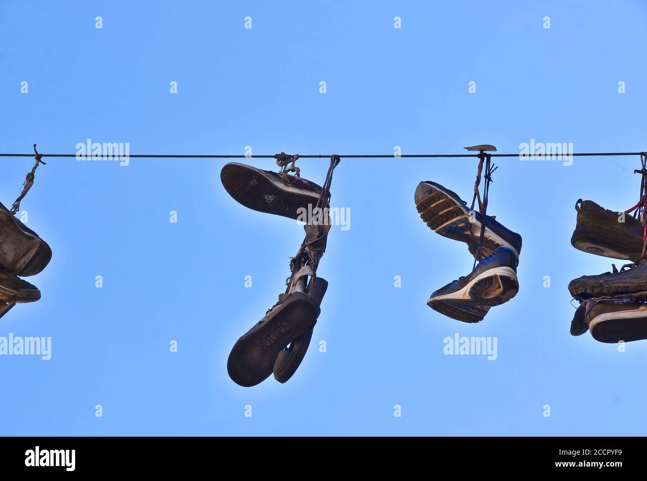 Many old shoes hanging on a string between two houses, a practice of ...