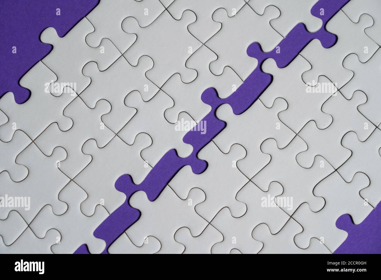 Fragment of a folded white jigsaw puzzle and a pile of uncombed puzzle ...