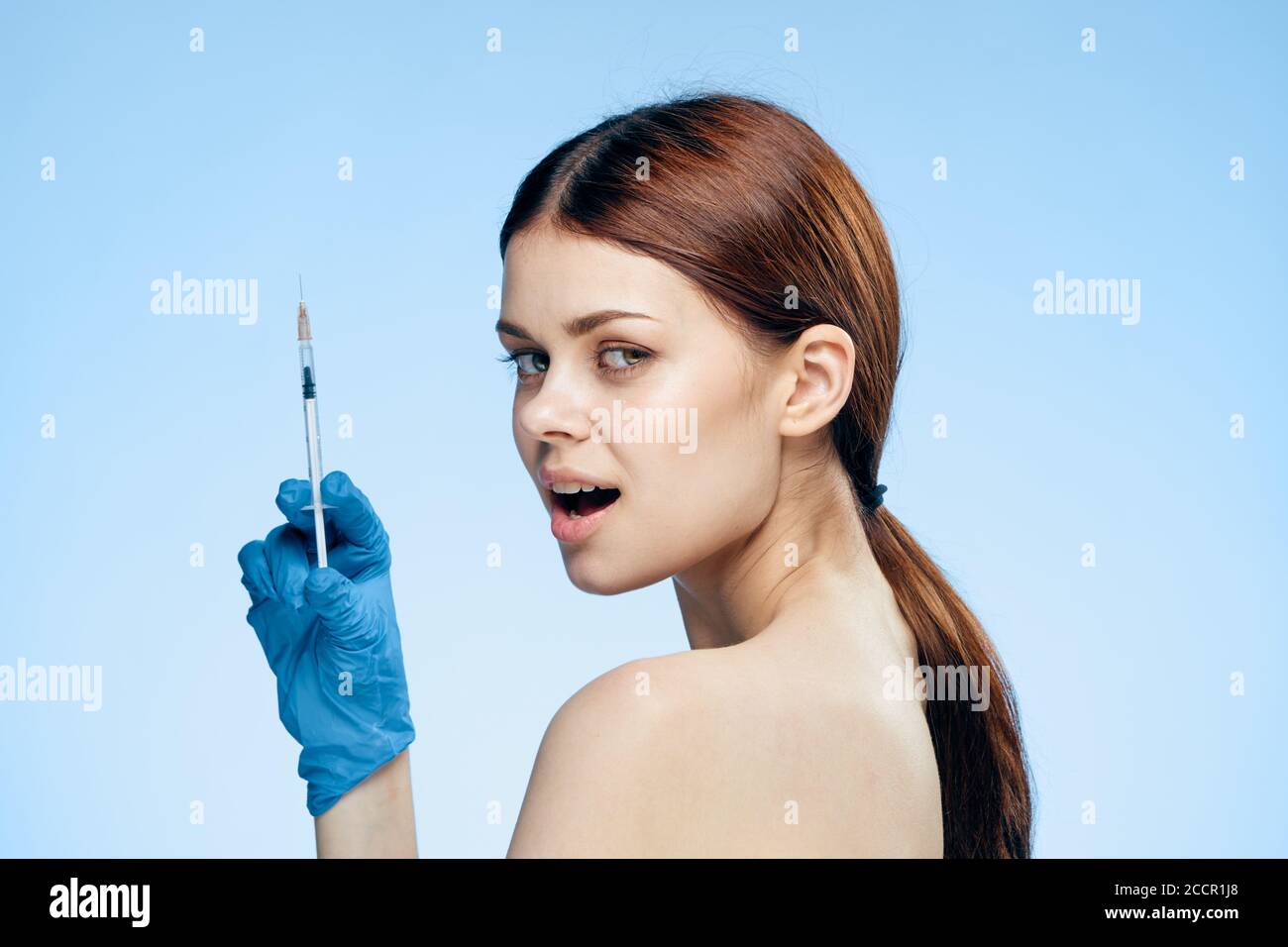 Woman in blue gloves with syringe in hand with botox injection ...
