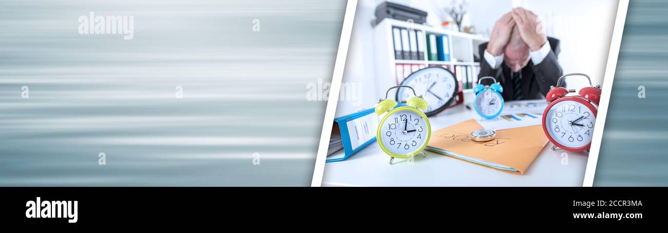 Stressed businessman behind his desk full of alarm clocks. panoramic banner Stock Photo - Alamy