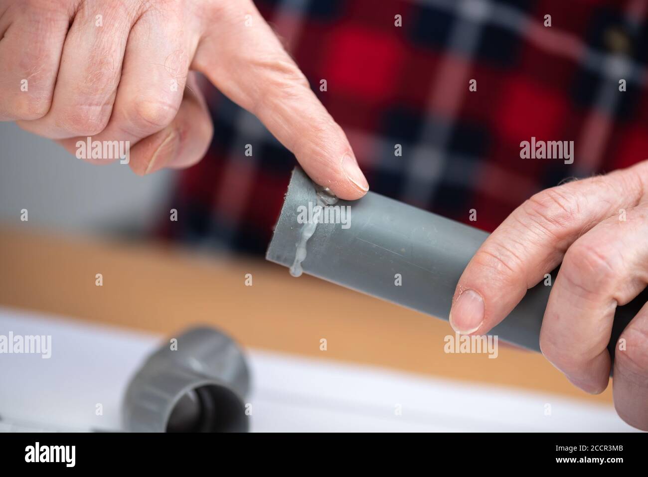 Plumber putting glue on a pvc pipe Stock Photo - Alamy