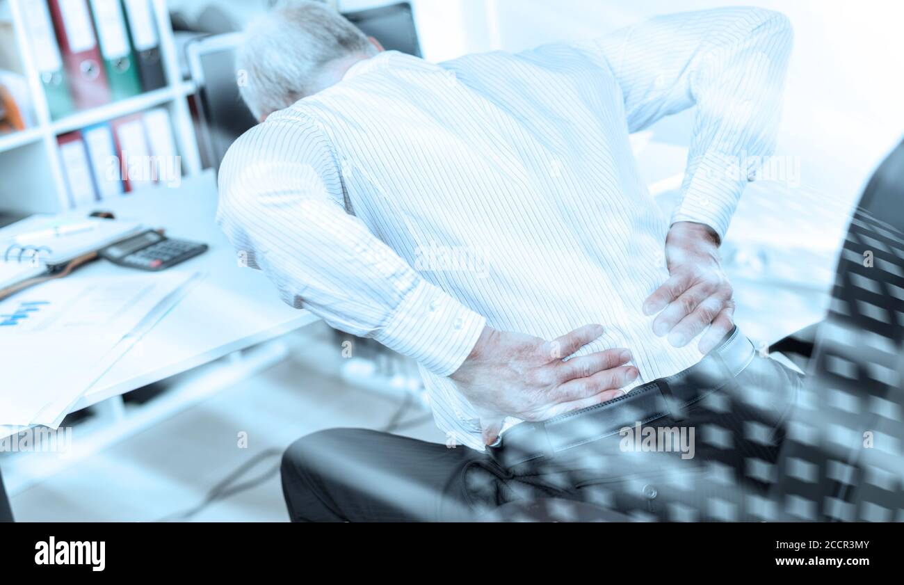 Businessman suffering from back pain at office; multiple exposure Stock ...
