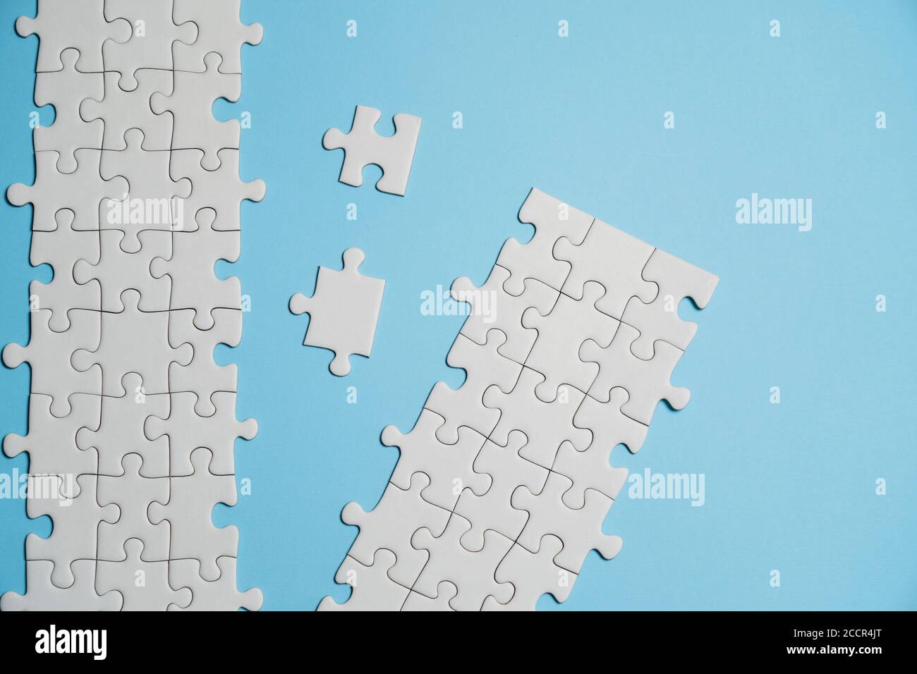 Fragment of a folded white jigsaw puzzle and a pile of uncombed puzzle ...
