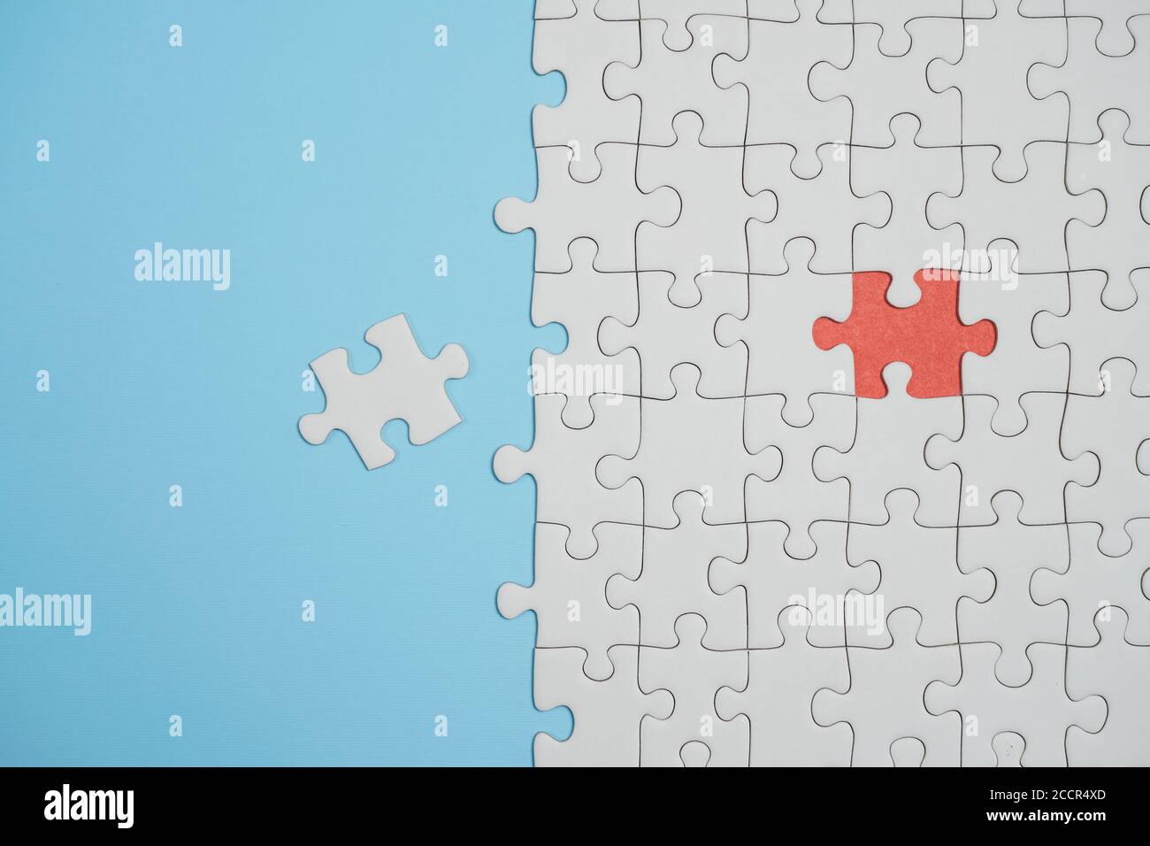 Fragment of a folded white jigsaw puzzle and a pile of uncombed puzzle ...