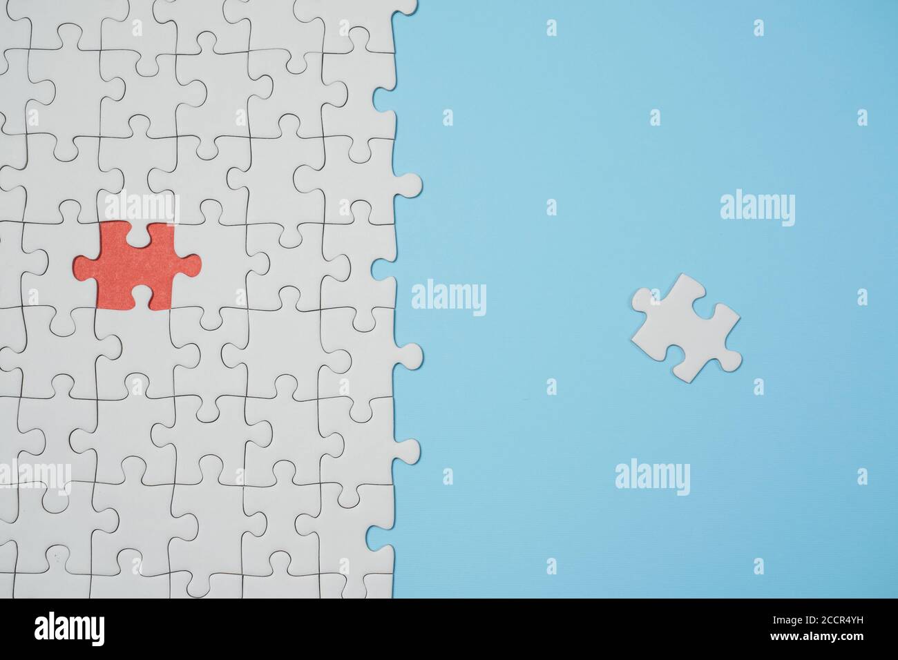 Fragment of a folded white jigsaw puzzle and a pile of uncombed puzzle ...