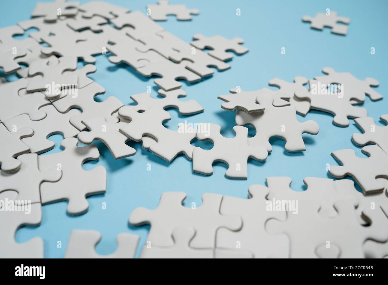 Fragment of a folded white jigsaw puzzle and a pile of uncombed puzzle ...