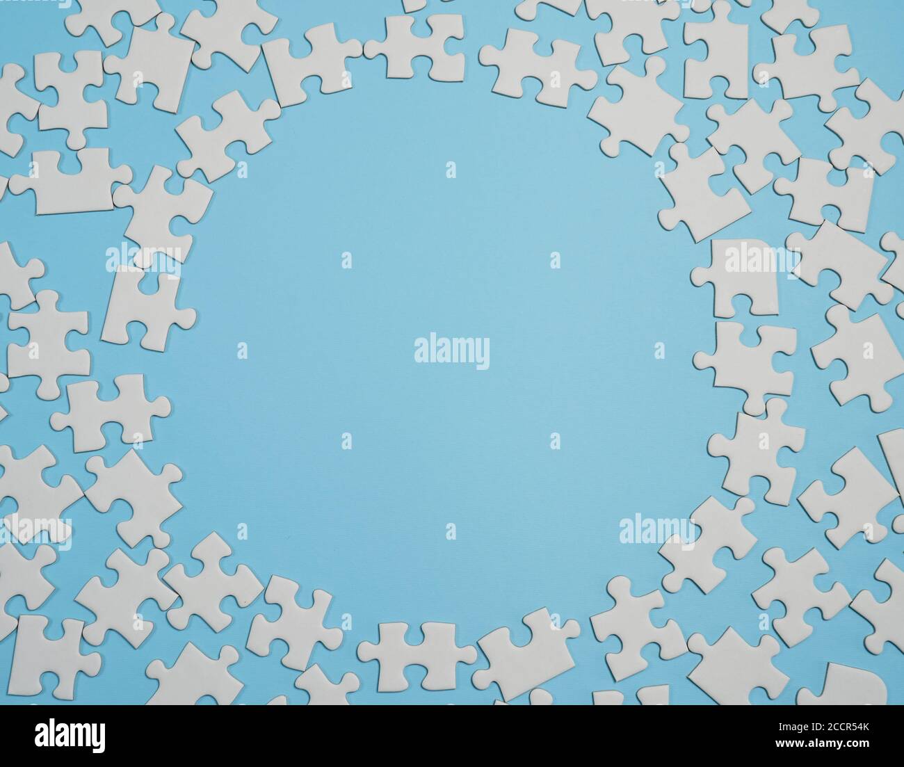 Fragment of a folded white jigsaw puzzle and a pile of uncombed puzzle ...