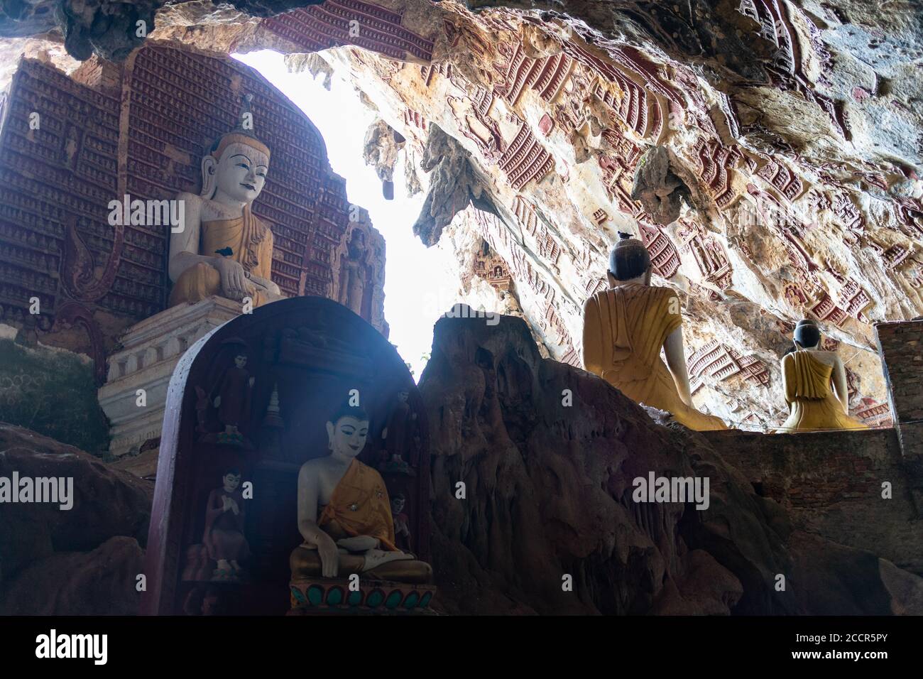 Statues of sitting Buddhas inside a cave. Carved figurines on the rock ...