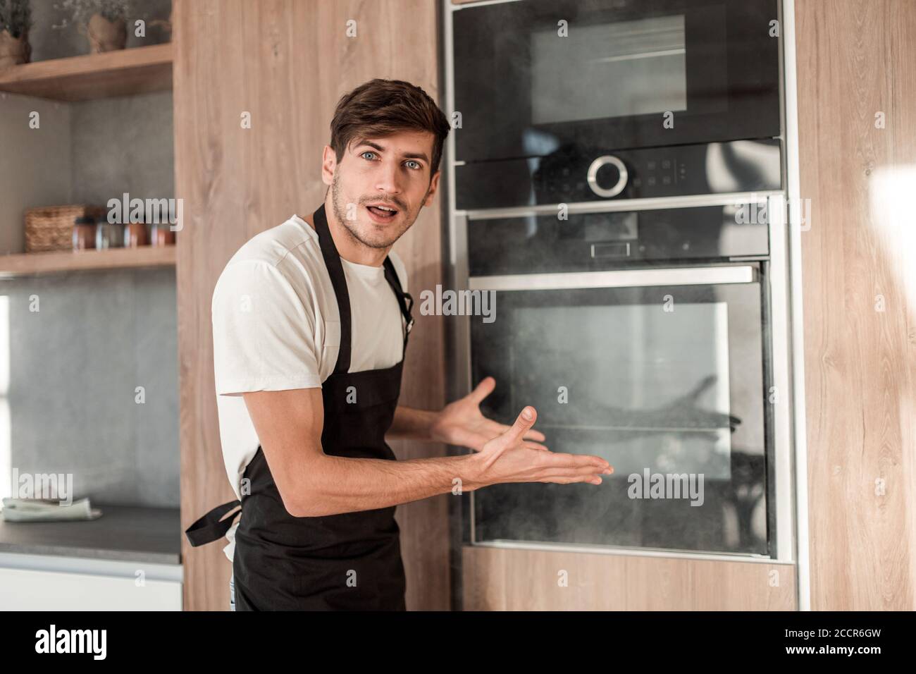 emotional young man standing near broken oven Stock Photo - Alamy