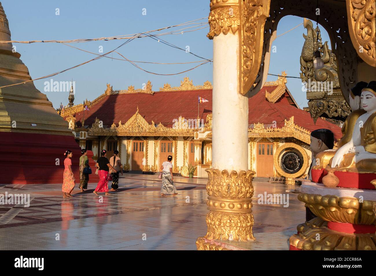 Buddhist women walking inside the U Zina Pagoda. Evening, sunset time ...