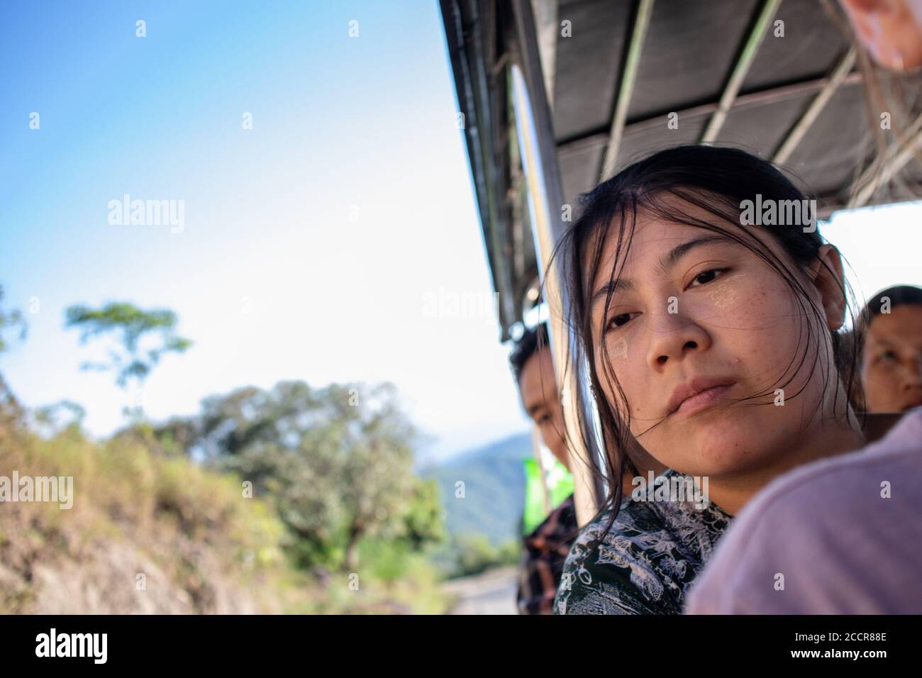 Burmese woman with traditional thanaka paste on her face. She is on an ...