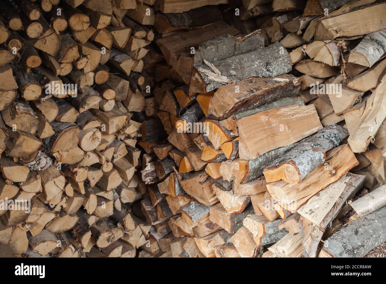 Stock of firewood, birch and alder chocks lay stacked in rural barn ...