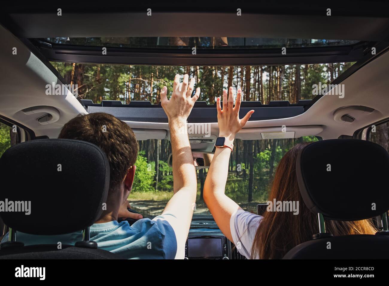 Couple in the car with their hands through open hatch on the roof ...