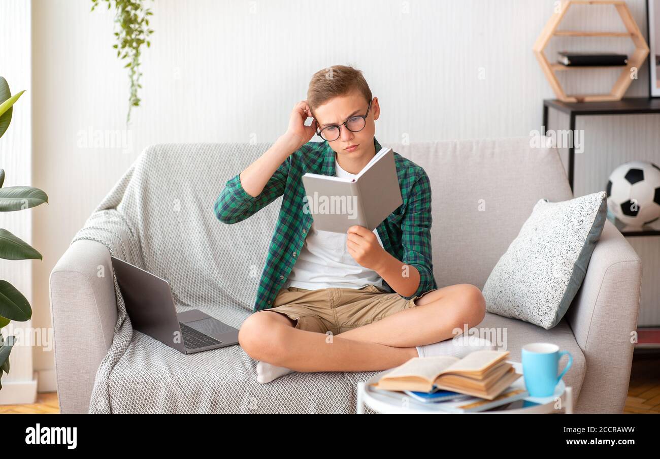 Confused nerd boy reading book, home education concept Stock Photo - Alamy