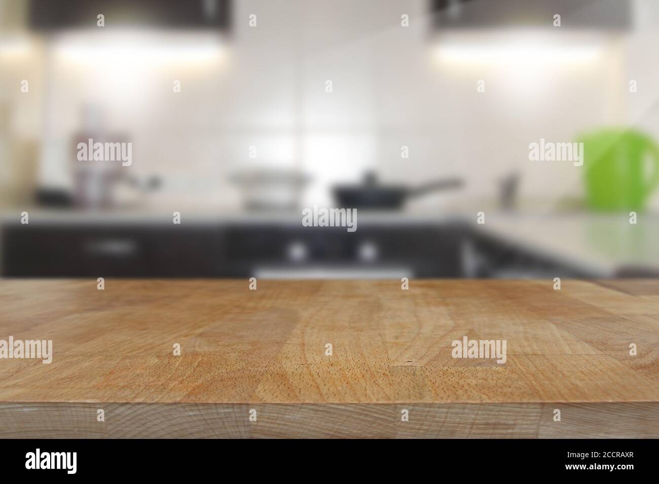 Wooden table, tabletop in the foreground with blurred kitchen interior ...