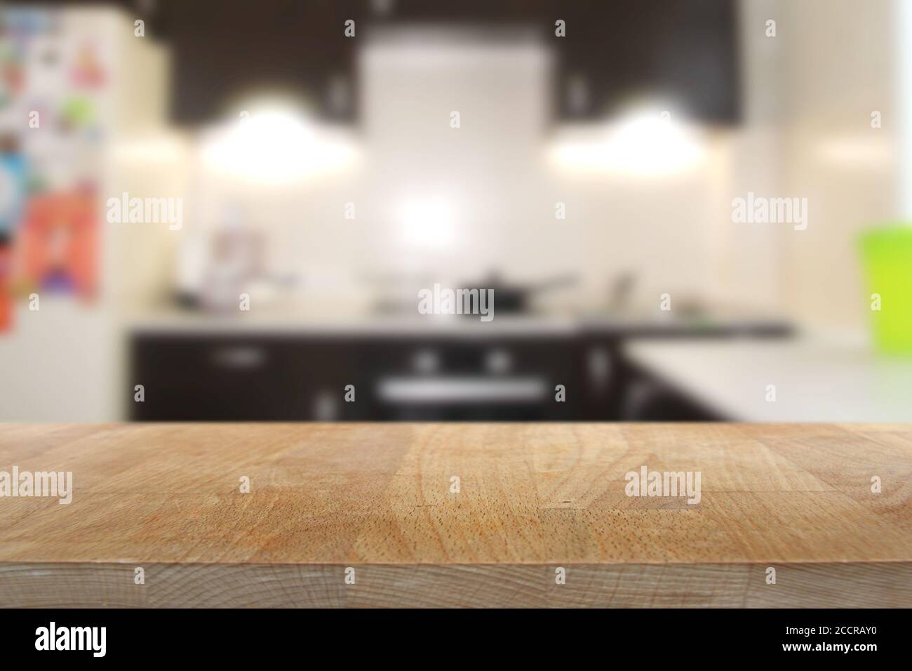Wooden table, tabletop in the foreground with blurred kitchen interior ...