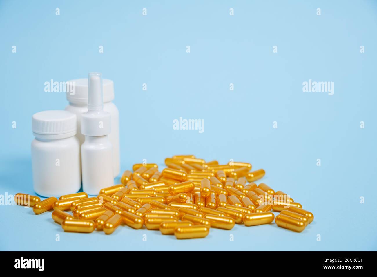 Golden pill capsules on a blue background Stock Photo - Alamy