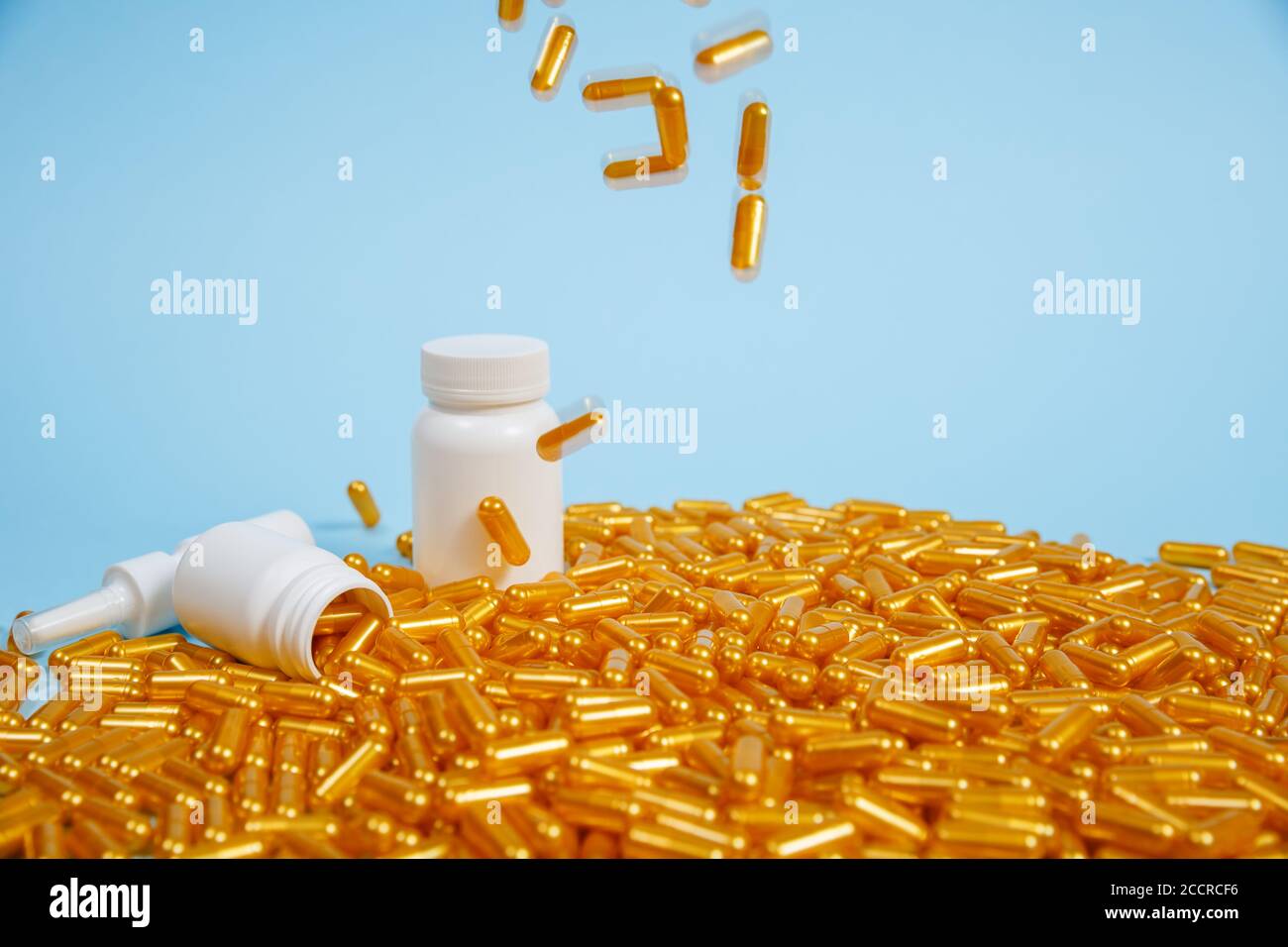 Golden pill capsules on a blue background Stock Photo - Alamy