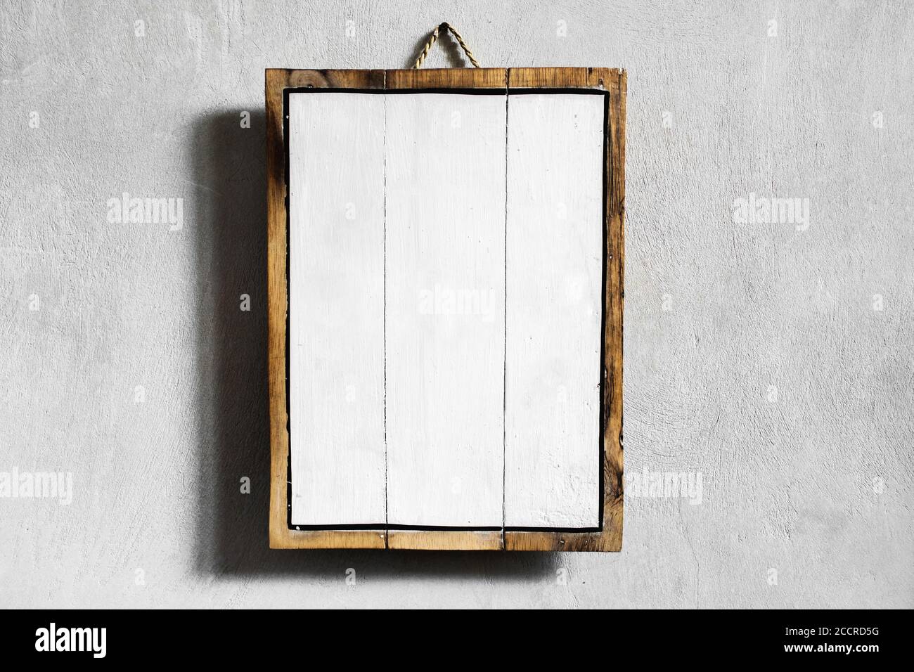 White wooden empty board hanging on gray concrete cement wall. Place ...