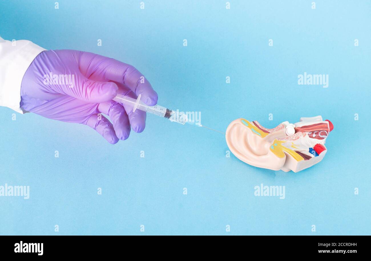 Otolaryngologist doctor holds a syringe on the background of the ear ...