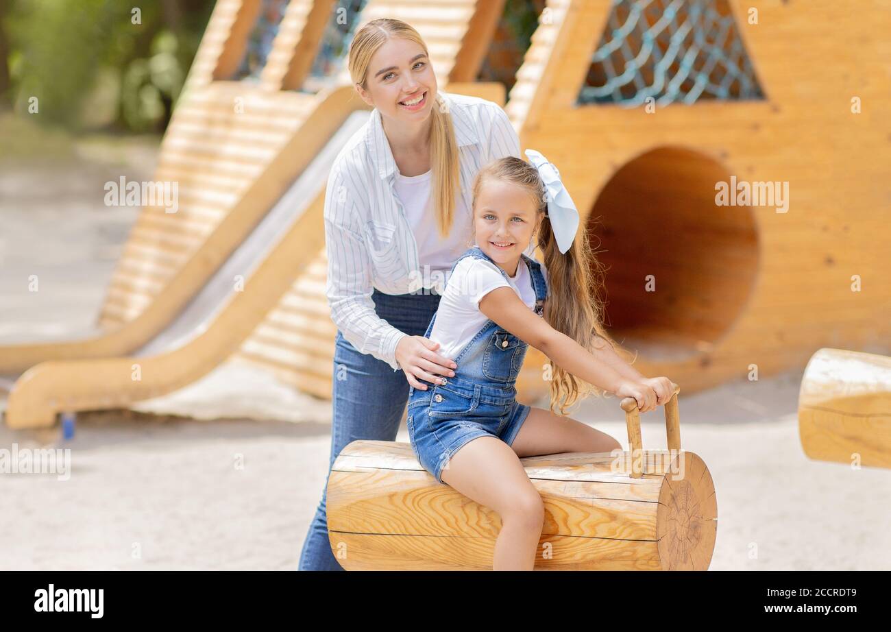 Mother Swinging Daughter On The Swing Having Fun On Playground Stock Photo - Alamy