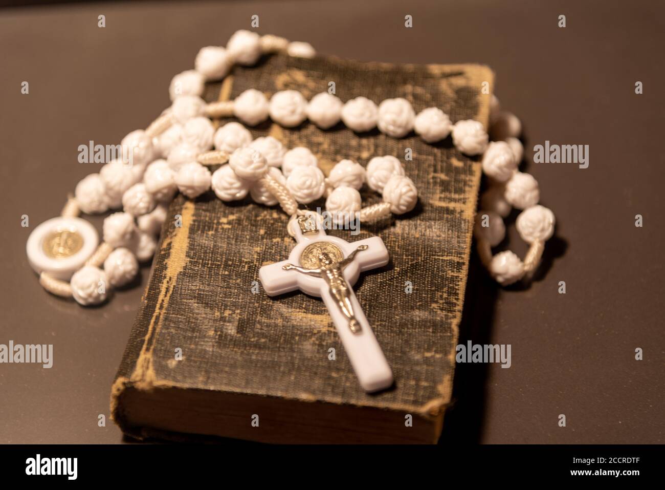 Old religious book. Symbols of Catholicism. Rosary and white crucifix ...