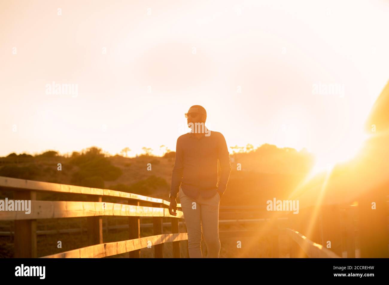 Happy latin man walking and enjoying the sunset with a natural ...