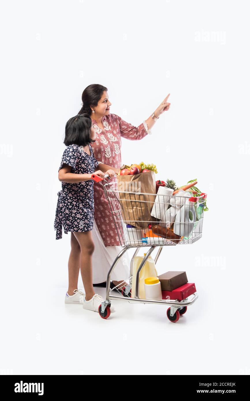 Indian mother and daughter with shopping cart or trolly isolated over ...