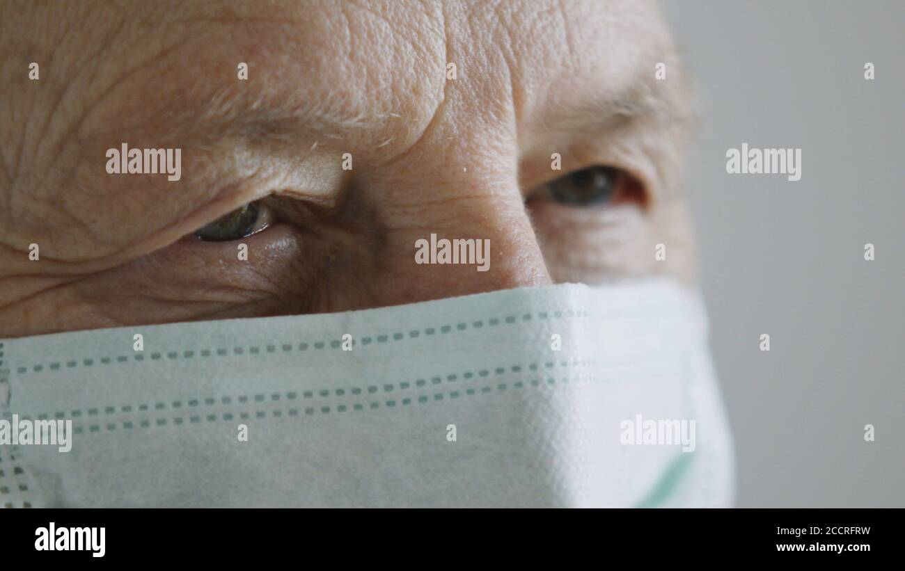 Extreme close up, eyes of a senior man with medical mask. Prevention of ...