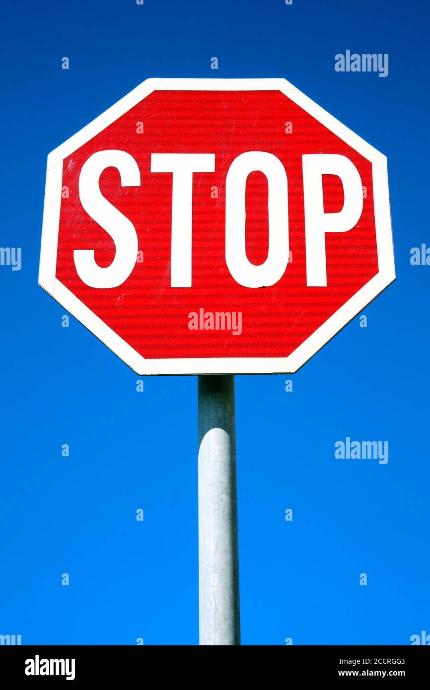 Red stop sign which is a halt traffic signpost with a clear blue sky ...