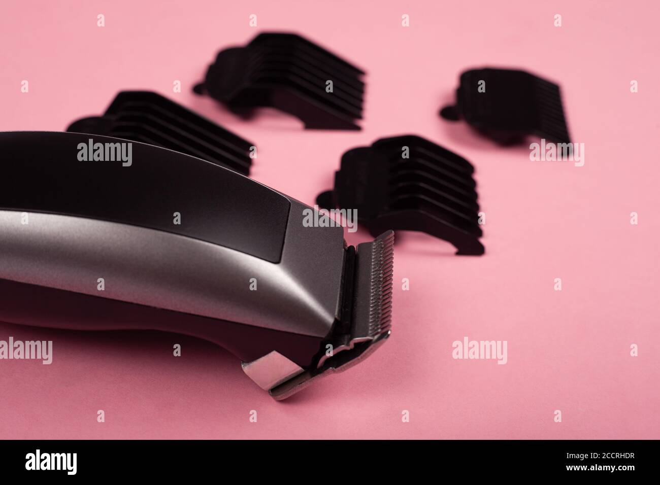 hair clipper with nozzles on a pink background close-up, hairdressing ...