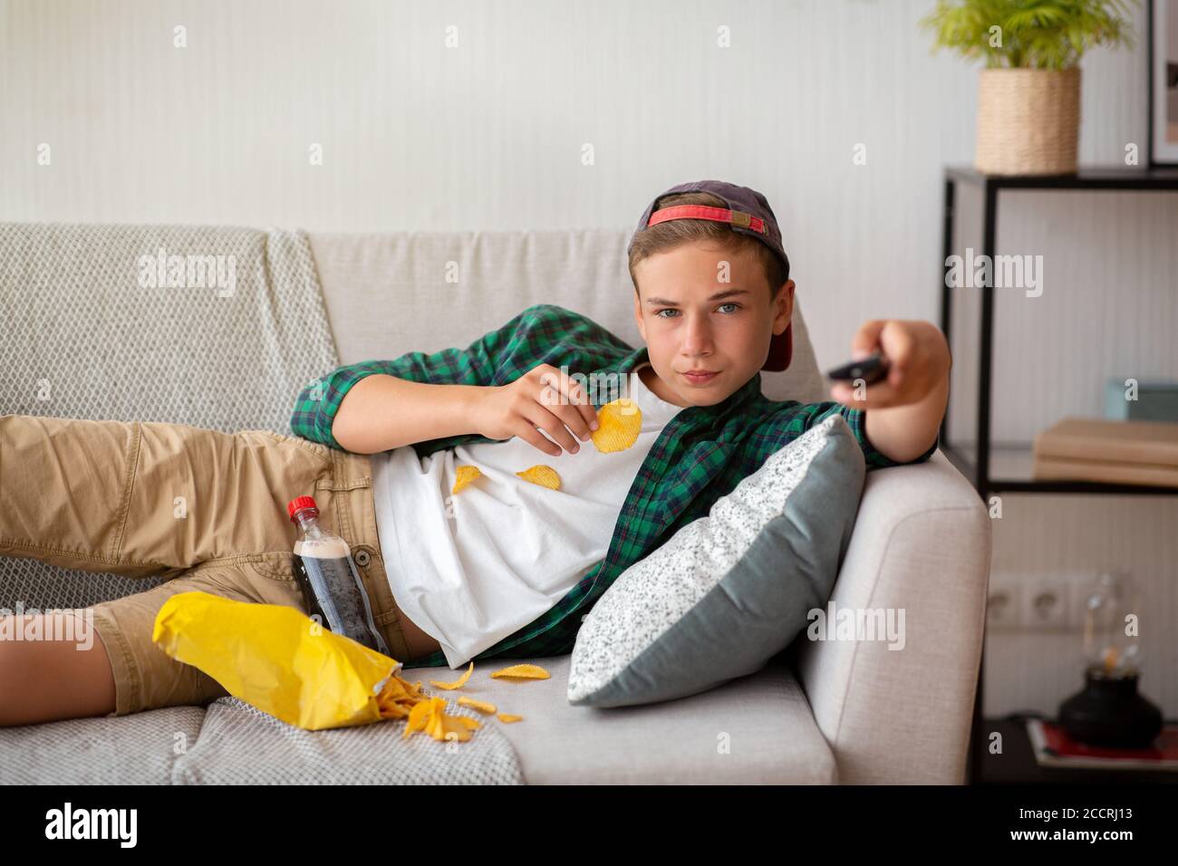 Teenager resting at home, watching TV and eating snacks Stock Photo - Alamy